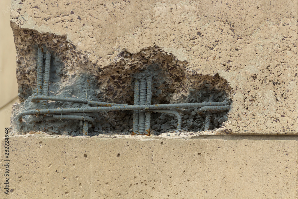 Broken concrete facade of the building showing the interior of metal ...