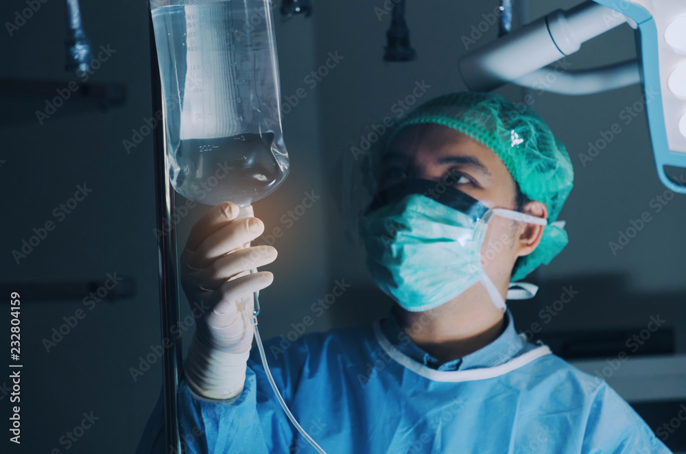 Doctor preparing saline drip bag for patient in operation room at ...