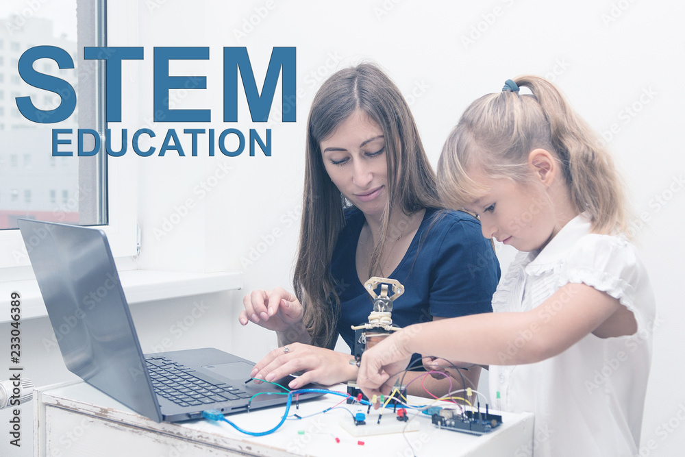 Schoolgirl studying with a teacher robotics, collects arduino robot and ...
