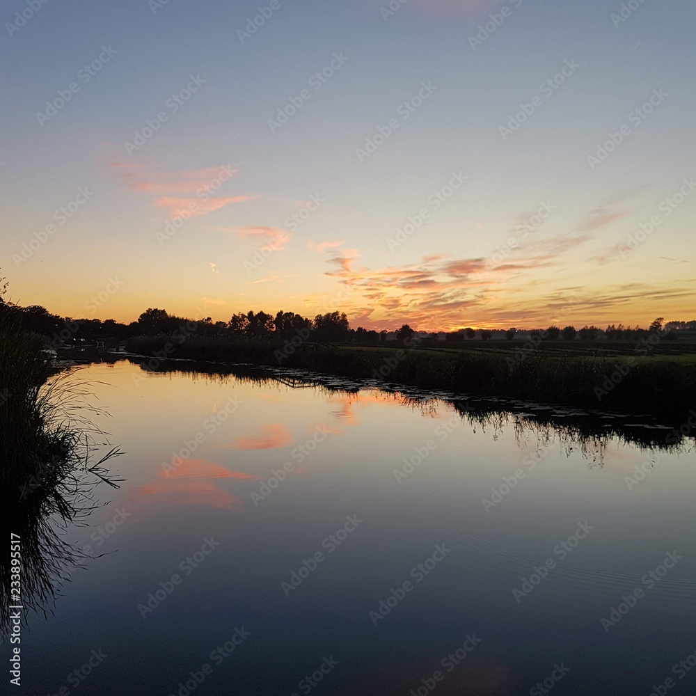 Atardecer en el rio con nubes rosas y reflejo perfecto en el agua Stock ...