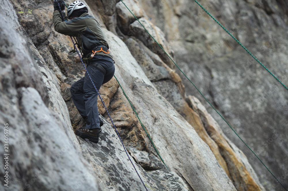 Climber pulls on the rock wall on a safety rope during competitions in ...