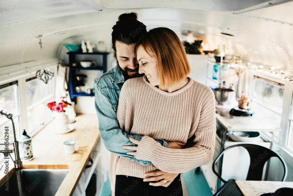 Cute hipster couple cuddling in converted school bus tiny home Stock ...