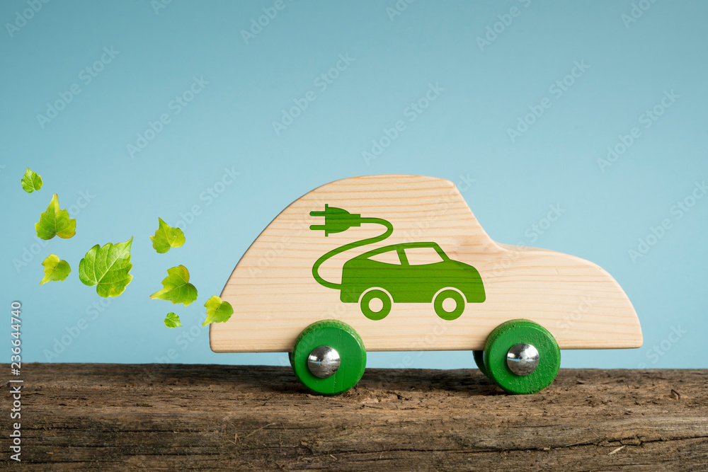 Concept of eco car. Wooden toy car with leaves and electric plug ...