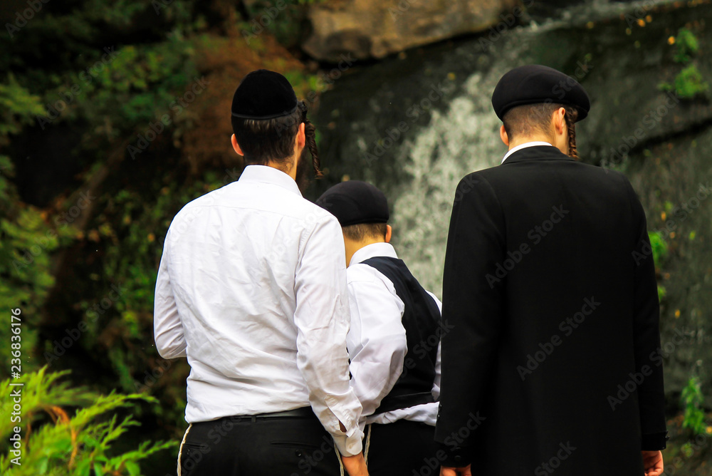 3 boys, a family of Hasidic Jews, in traditional clothes stand in front ...