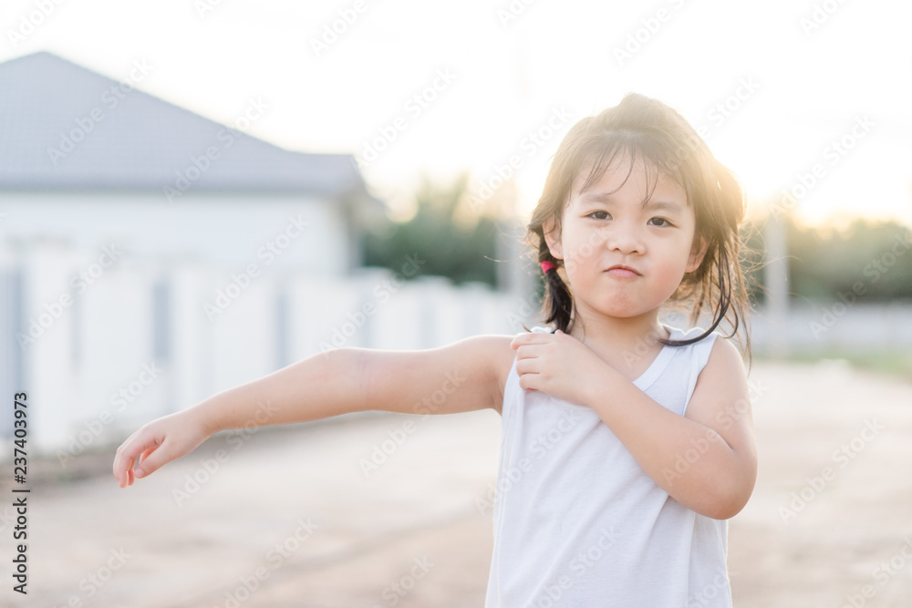 Little asian girl scratching an itch with hand outdoor.Kid's hand ...