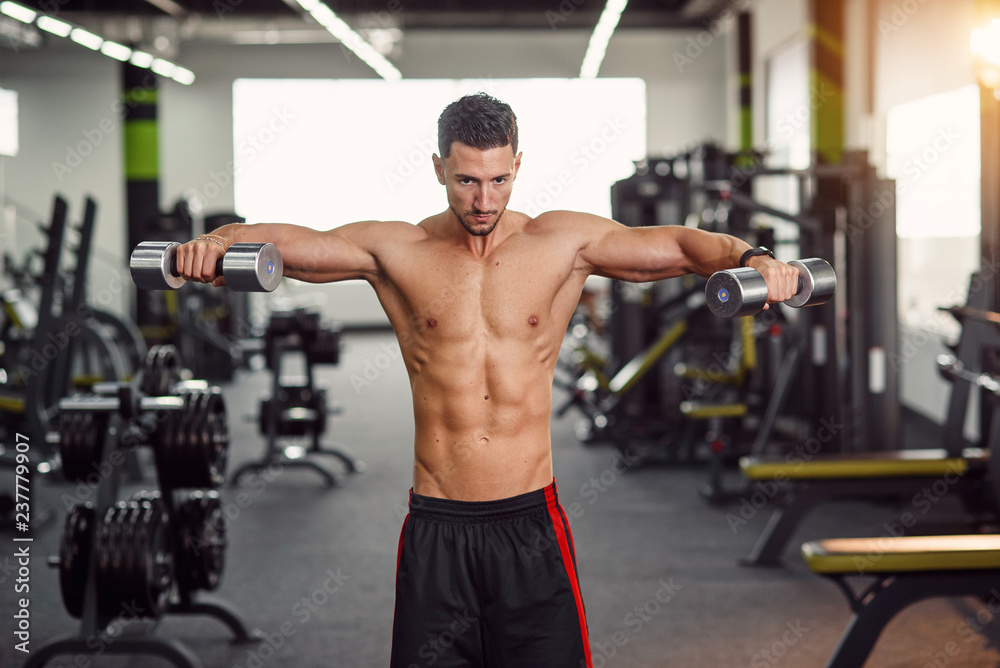 Strong healthy man training his shoulders in the gym. Isolated exercise ...