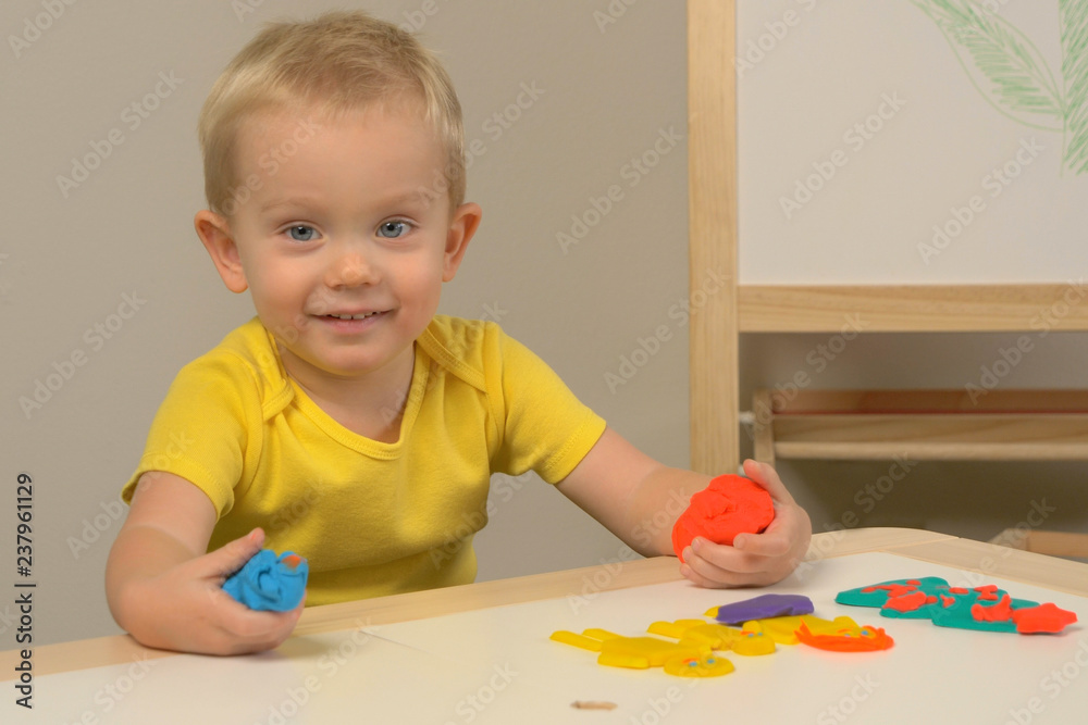A two years old preschool child making figures from modeling clay ...