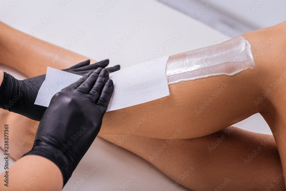 Depilatory master wearing black gloves making wax depilation Stock Photo | Adobe Stock