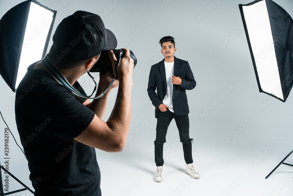 Photographer shooting model in studio with softboxes. Young man ...