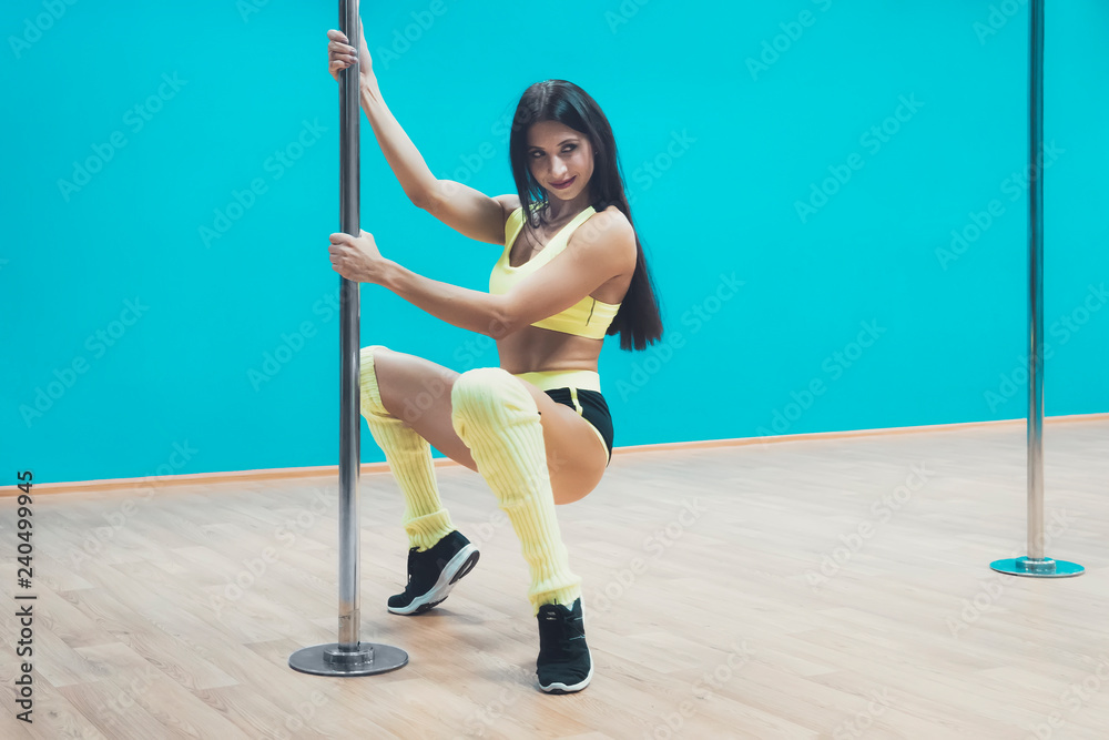 Stock-Foto „Young sexy poledancer holding pole and squating at dance class background ...