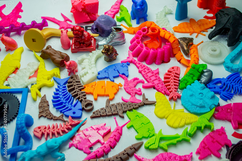 Many bright multi-colored objects printed on 3d printer lie on flat ...