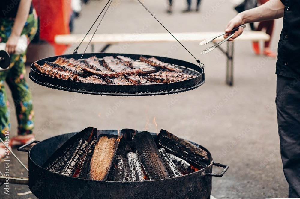 grilled meat. man holding steel tongues and roasting beef pork on big ...