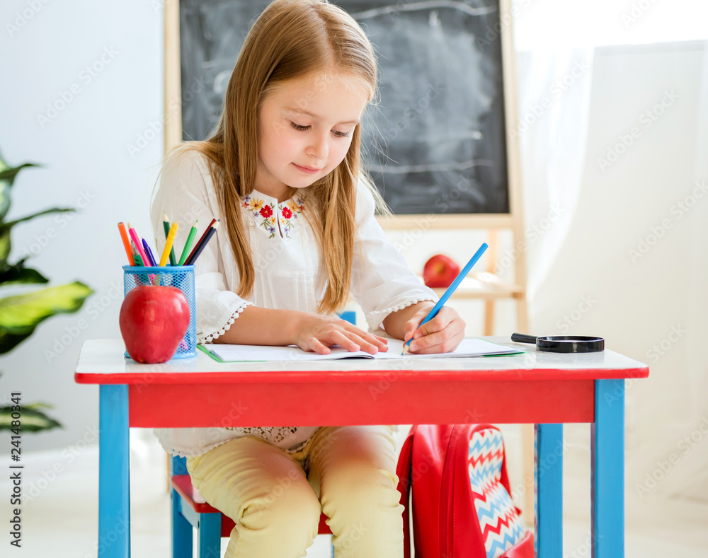 Little blond girl writing classwork in the school classroom Stock Photo ...