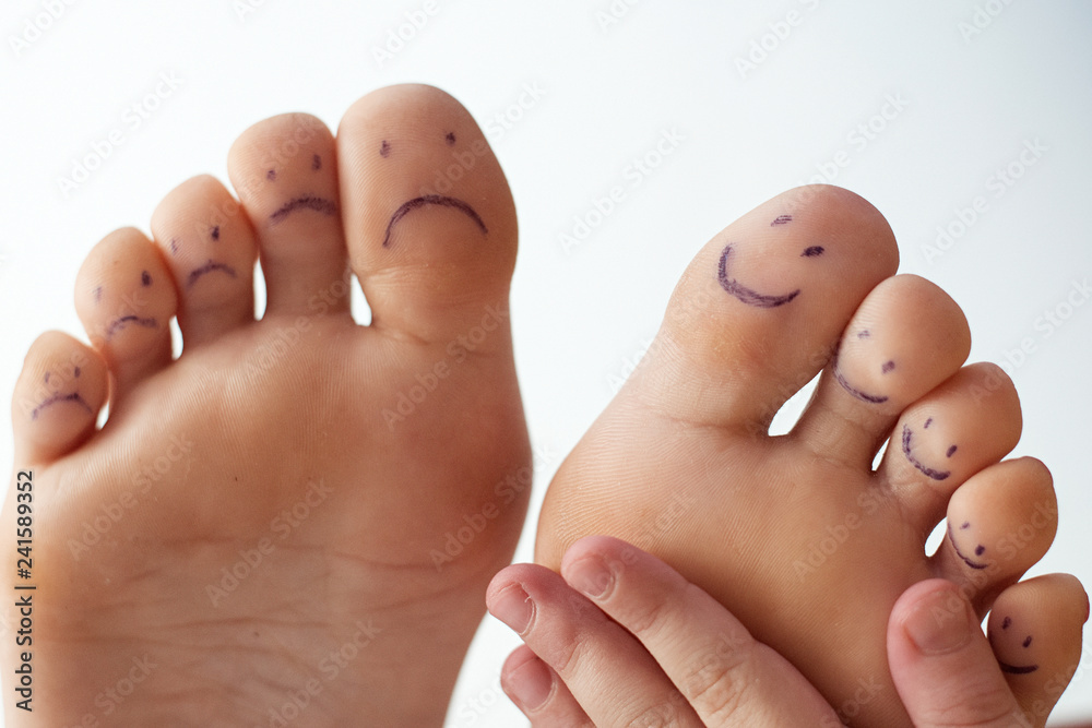 Female toes with painted smileys and children's hands. Foot care ...