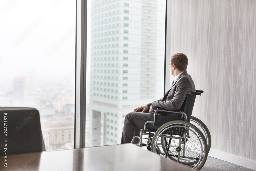 Thoughtful disabled businessman looking through window in boardroom at ...