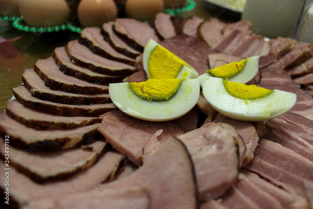 Slices of ham and boiled egg is cut into four parts in a selective ...