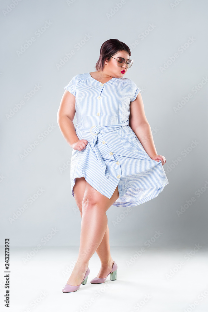 Plus size fashion model in striped dress, fat woman on gray background ...
