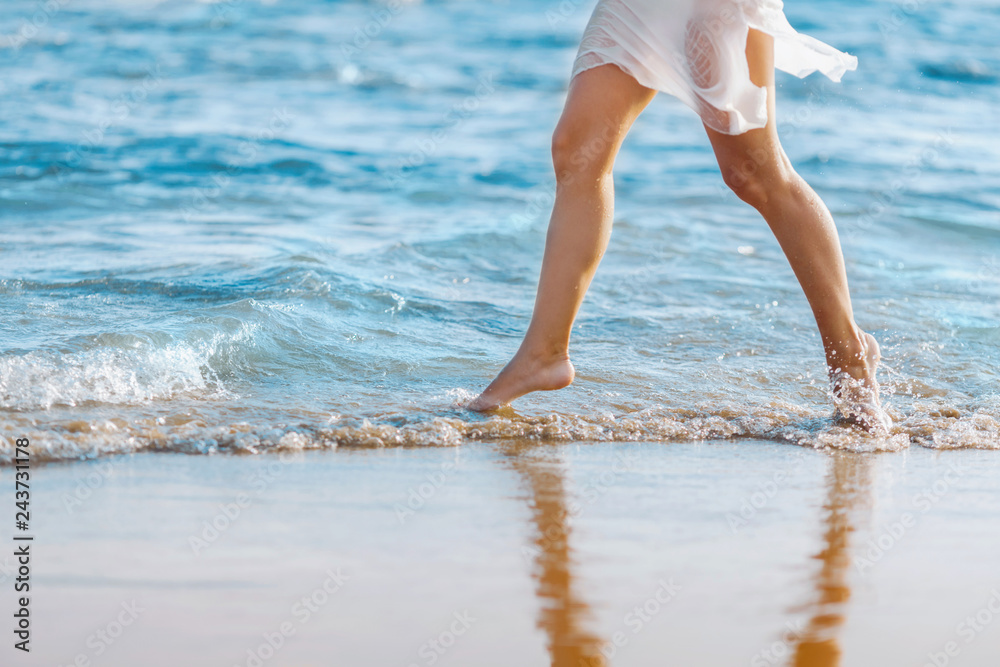 Foto Beautiful young girl running on the beach barefoot in the water ...