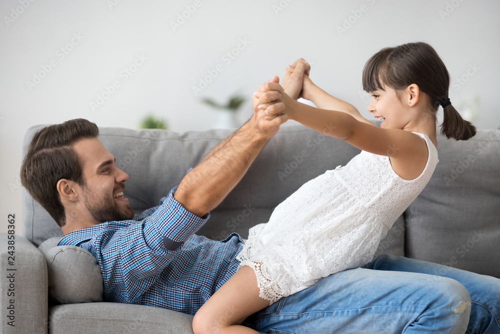 Carefree excited child girl and her father playing holding hands relaxing together, happy dad ...