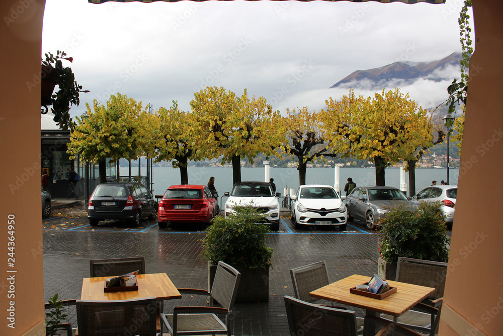Two tables of street cafe with a view of yellow trees next to the Como ...