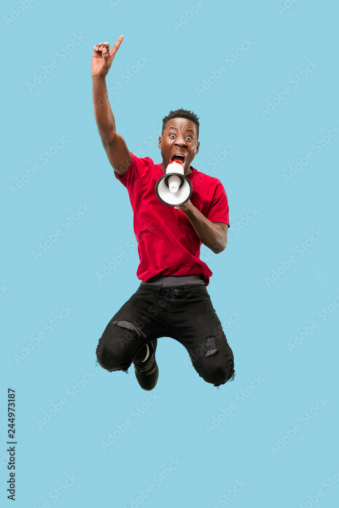 Soccer fan jumping on orange background. The young african man as ...