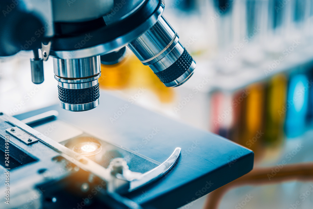 Microscope in microbiology lab with laboratory glassware background for ...