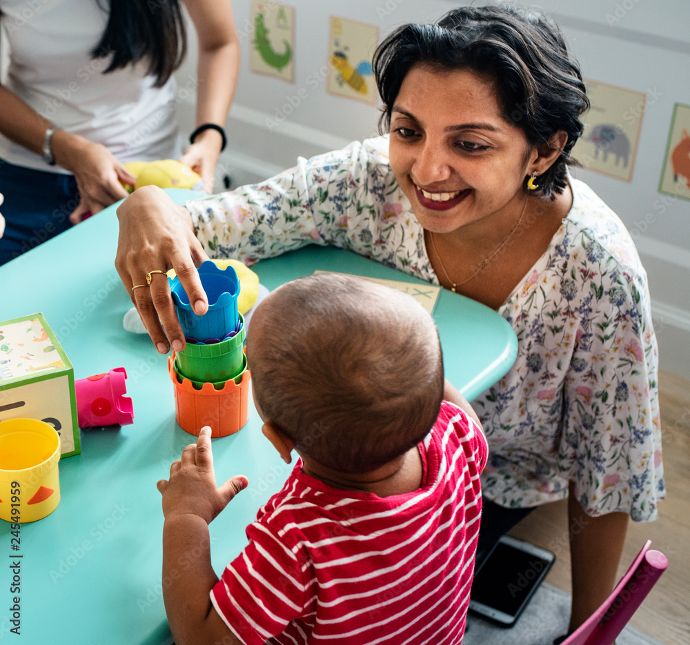 Child building blocks with a teacher in the nursery Stock Photo | Adobe ...