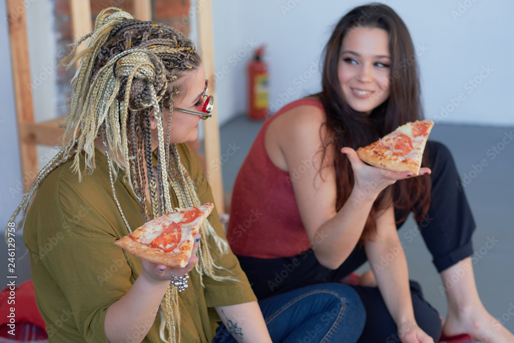 two girls eat pizza in the room on the bed. junk food. Stock Photo ...