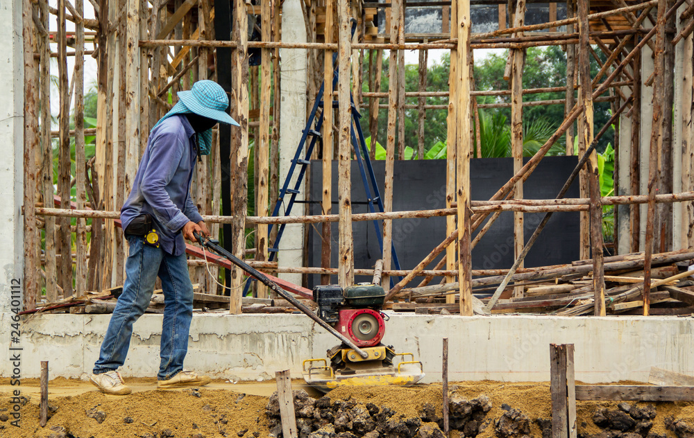 worker at sand ground compaction with vibration plate compactor machine ...
