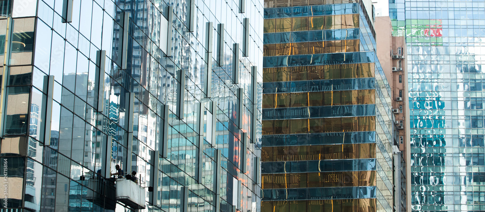 Workers crane cradle clean windows glass of high building under sun day ...