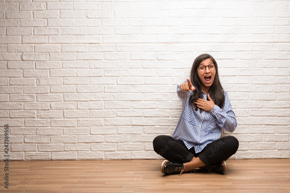 Young indian woman sit against a brick wall shouting, laughing and ...