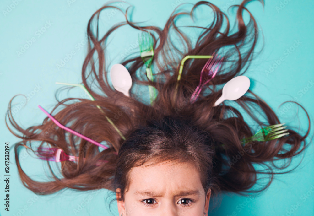 Little girl closing her eyes in surround of plastic trash, plastic bags ...