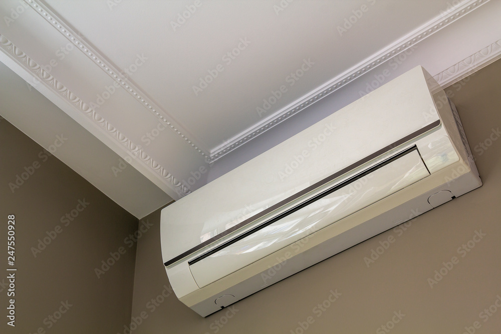 Cool air conditioner installed in room interior on white ceiling and ...