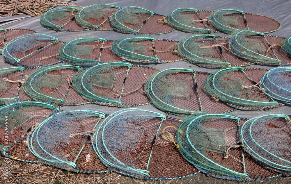 Folded fish traps lying on the shore in a fishing village on Itoshima ...