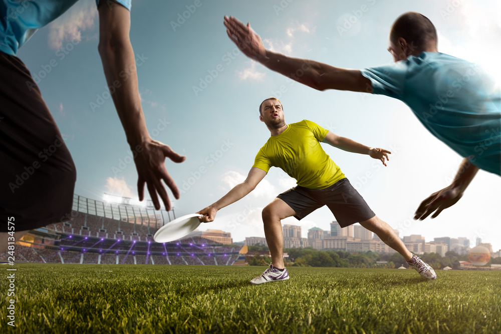 Two team play ultimate frisbee in stadium. One athlete give passes ...