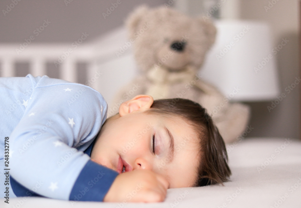 Close up portrait of cute little baby boy in light blue pajamas ...