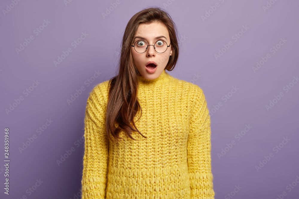Puzzled scared girl with jaw dropped out, has widely opened eyes, dark ...