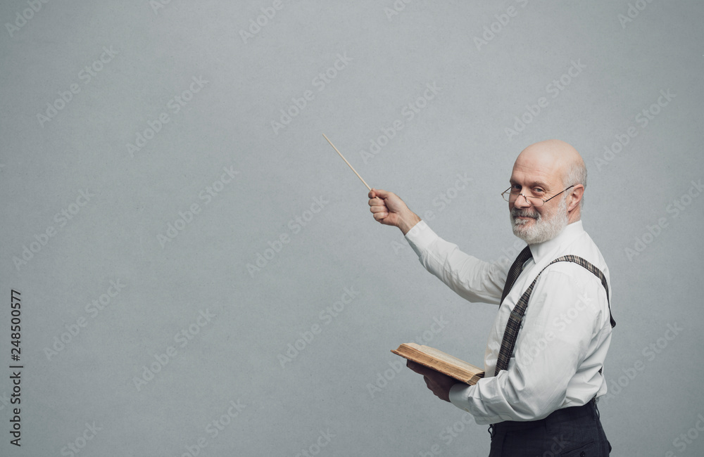 Smiling confident professor teaching and pointing at the blackboard ...