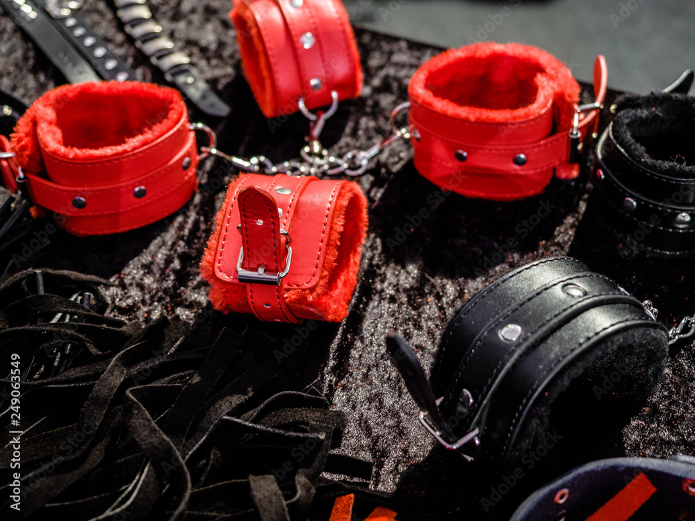 Concept image with red hand cuffs, sex shackle on black silk. BDSM is a ...