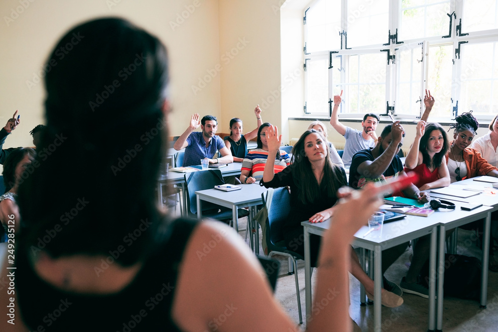 Students raising hands to answer questions asked by teacher in ...