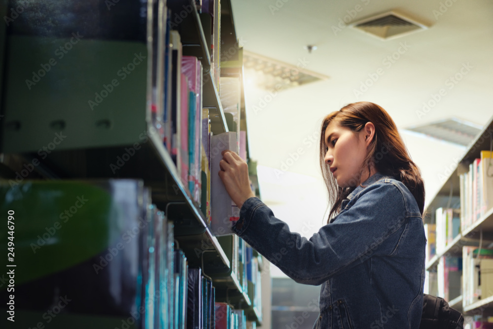 Asian Student searching for textbook in the bookshelf in the ...