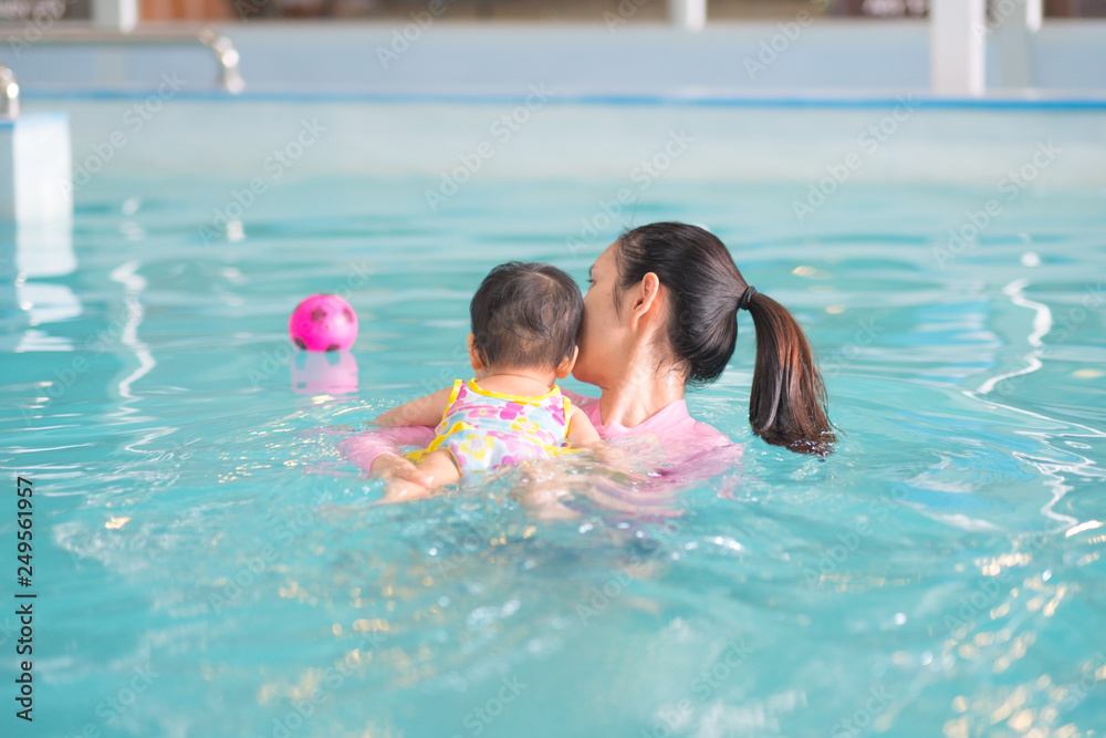 Asian baby girl reach for a toy in swimming pool.Baby swimming concept ...