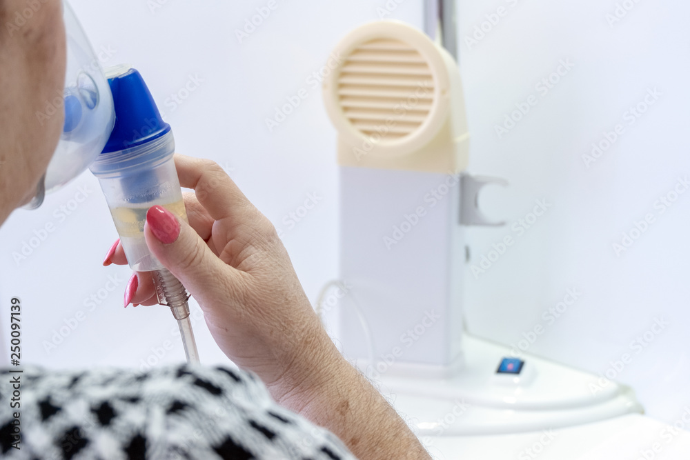 A female hand closes the lips and nose with an inhaler mask to breathe ...