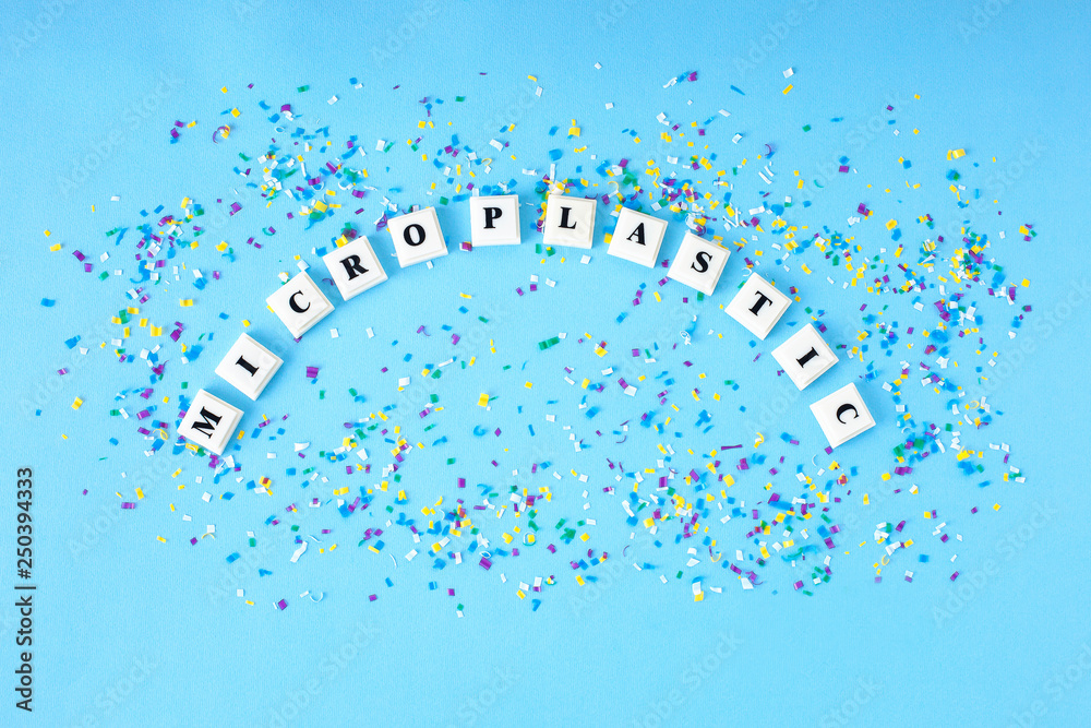 Word MICROPLASTIC around small plastic particles on a blue background ...