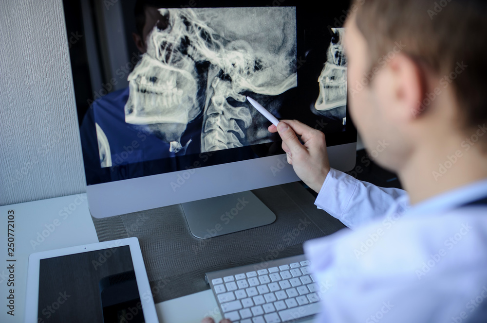 back view of a male radiologist examining neck x-rays (cervical ...
