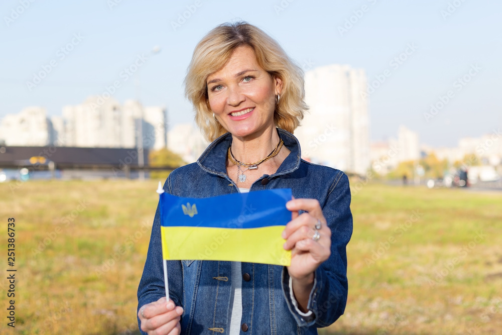 Mature Woman With The Flag Of Ukraine Against The Blue Sky And The City Mature Woman With The Flag Of Ukraine Against The Blue Sky And The City