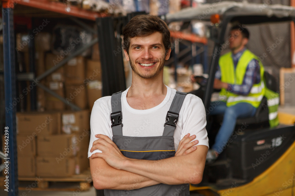 Front view of handsome workerof warehouse smiling, posing and looking ...