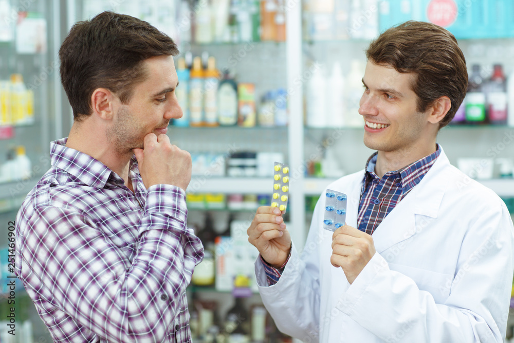 Pharmacist in white coat holding blister packs with yellow and blue ...