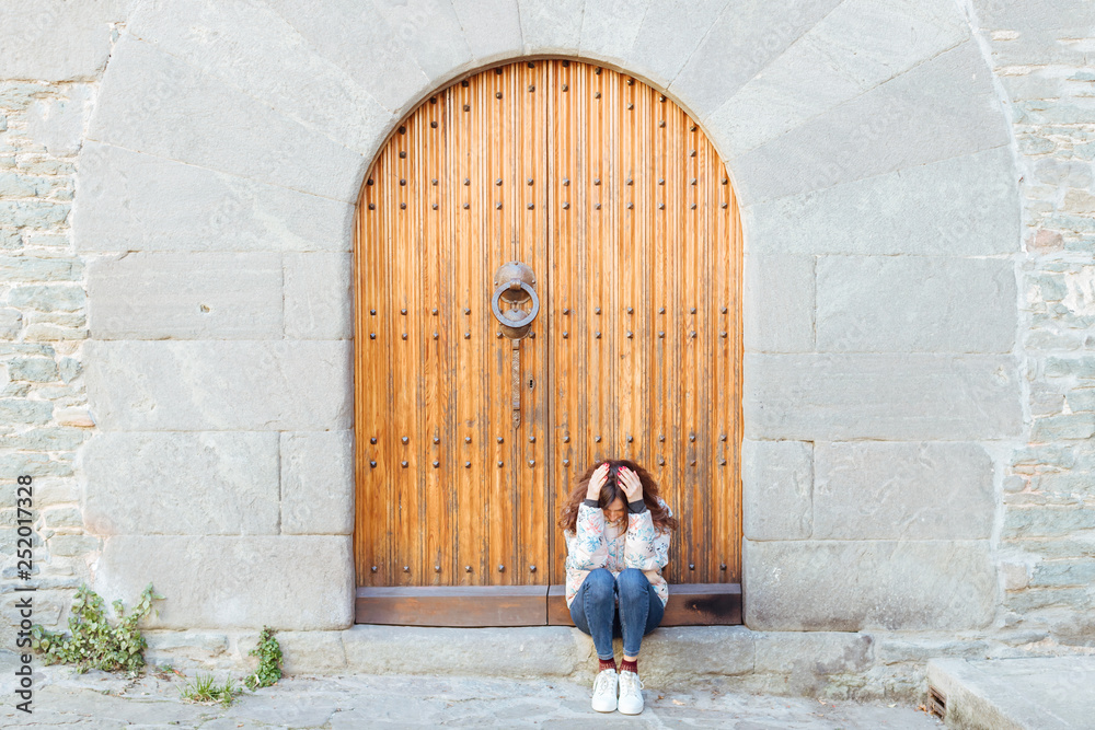 Foto de Stock Sad girl sitting on threshold of the closed door Bend ...