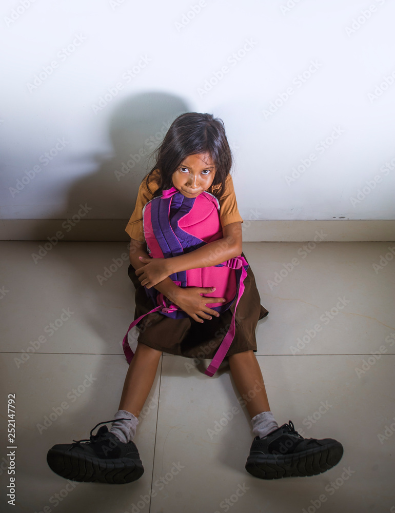 sad and depressed 8 or 9 years old child in school uniform sitting on ...
